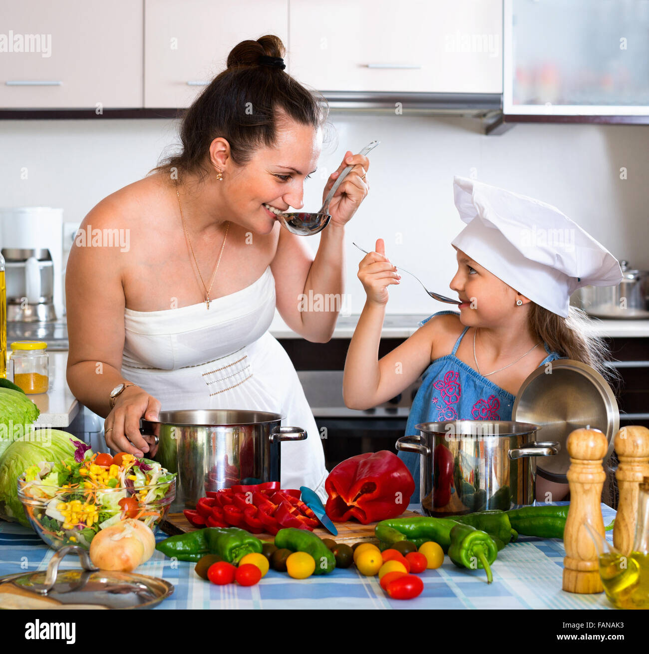 Cheerful happy girl helping mother to cook at the kitchen Stock Photo ...