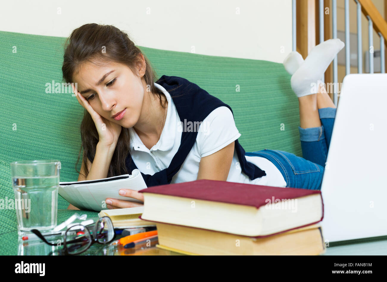 Nervous teenager doing homework on the couch in home Stock Photo - Alamy