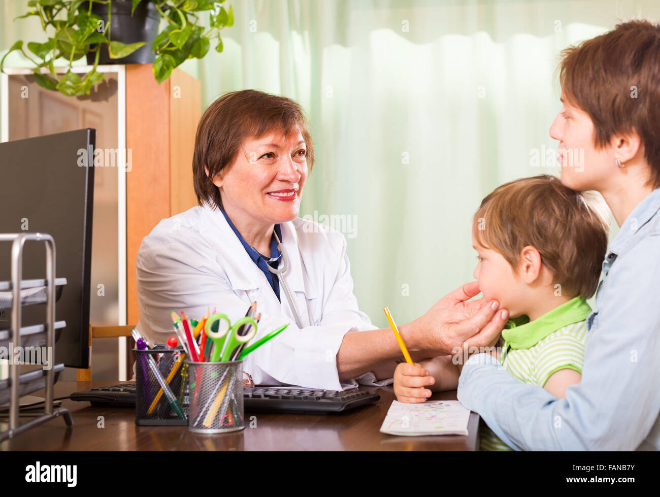 Smiling mature pediatrician doctor examining child at clinic office ...