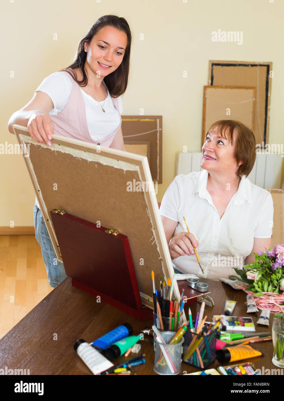 Smiling female artist draws a picture for her client at studio Stock ...