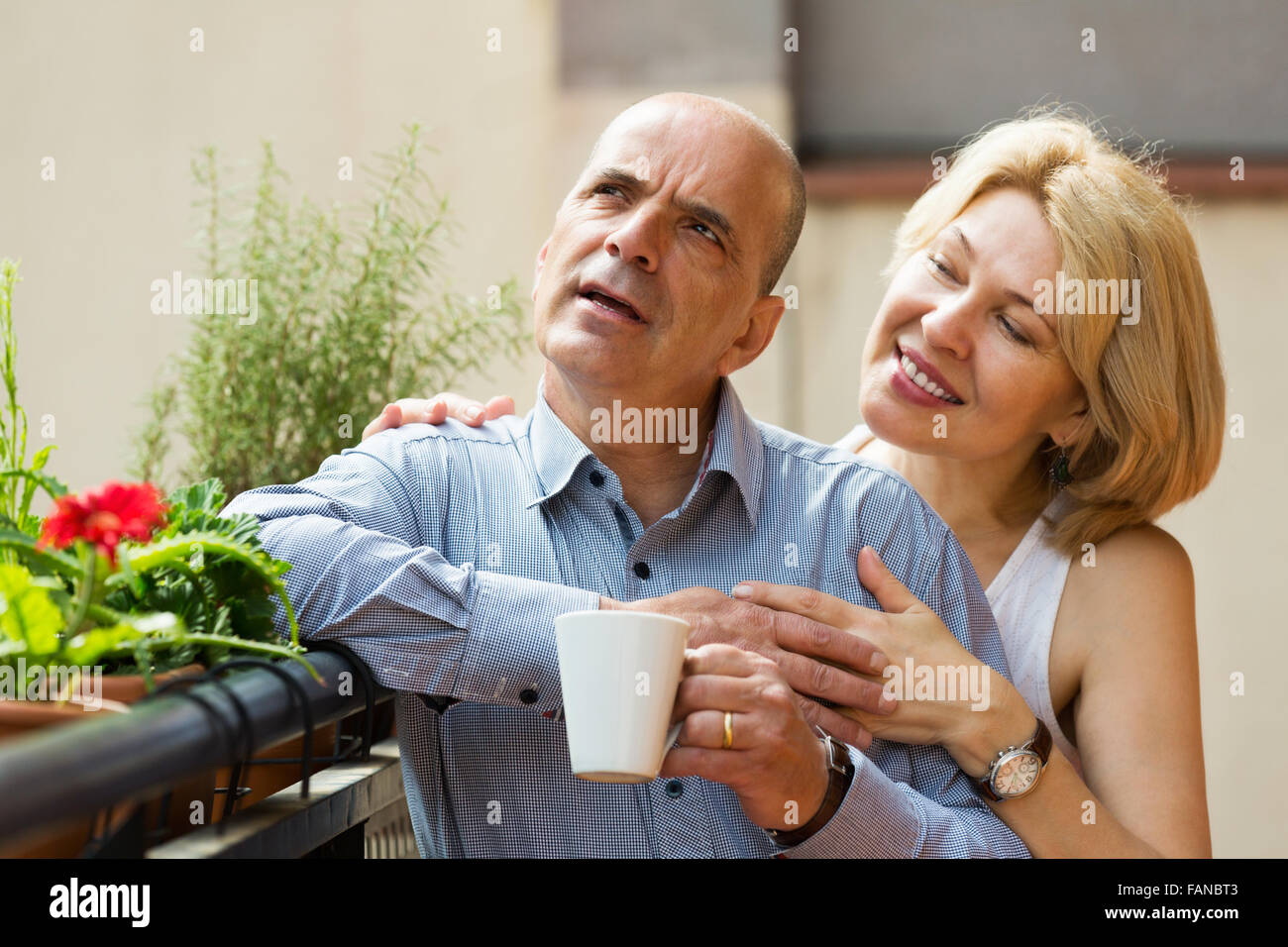 Positive elderly couple having morning coffee at balcony and smiling ...