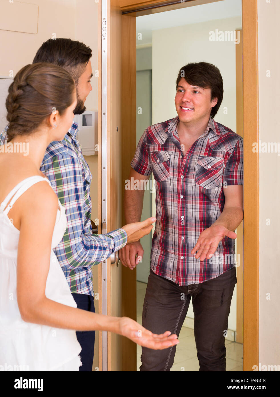 young russian family couple inviting friend in the apartment Stock ...