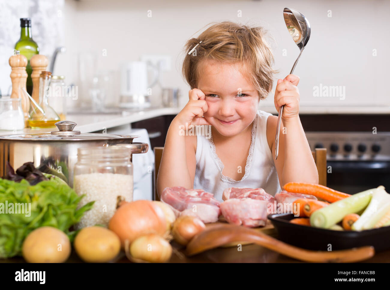Happy smiling baby girl cooking with meat at home Stock Photo - Alamy