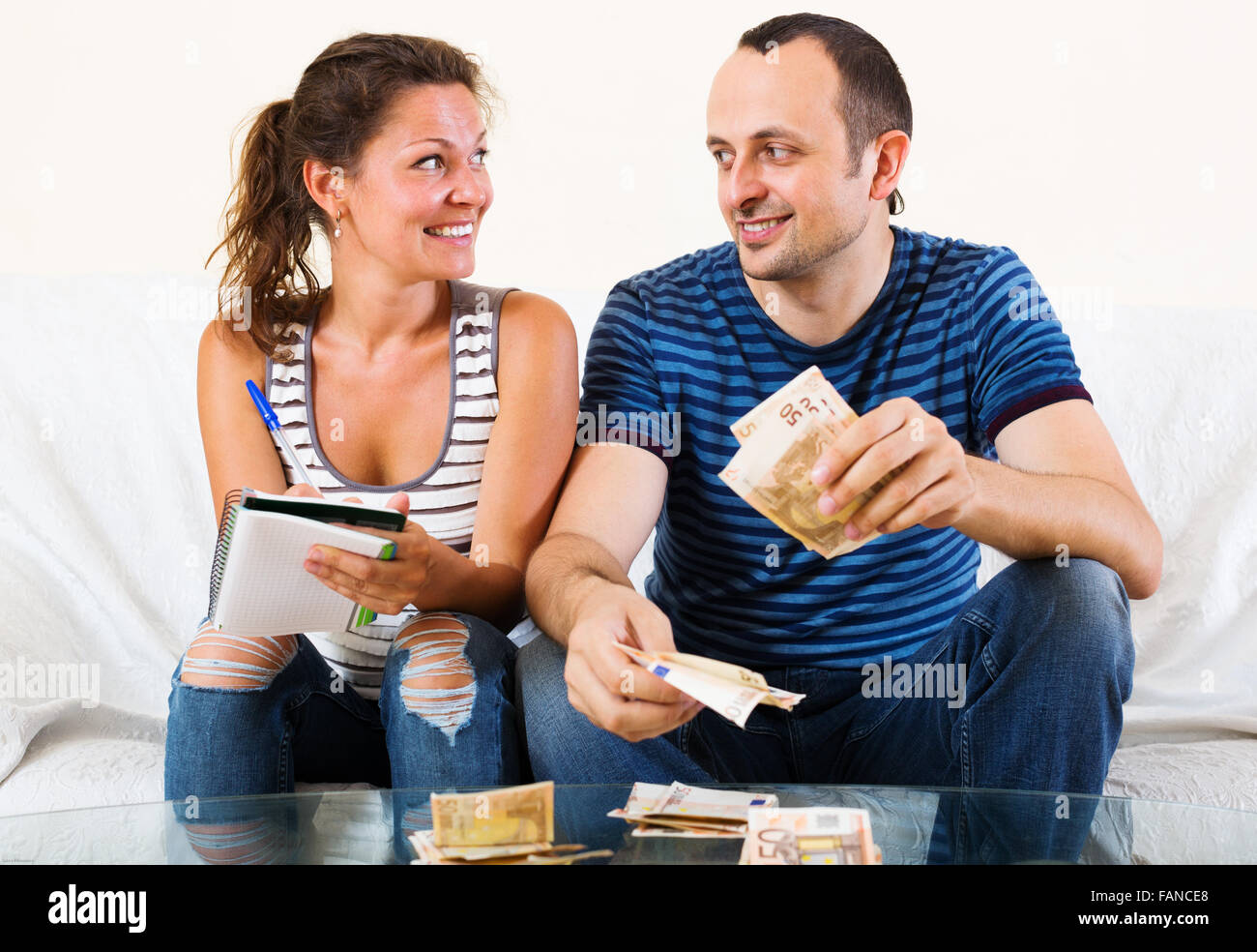 Sly wife asking smiling man money for shopping at sofa Stock Photo - Alamy
