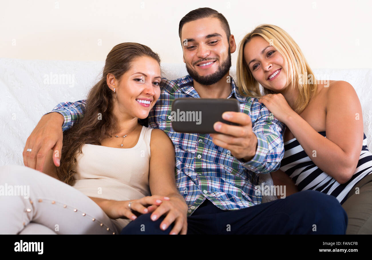 Cheerful young friends making selfie at home using camera in phone ...