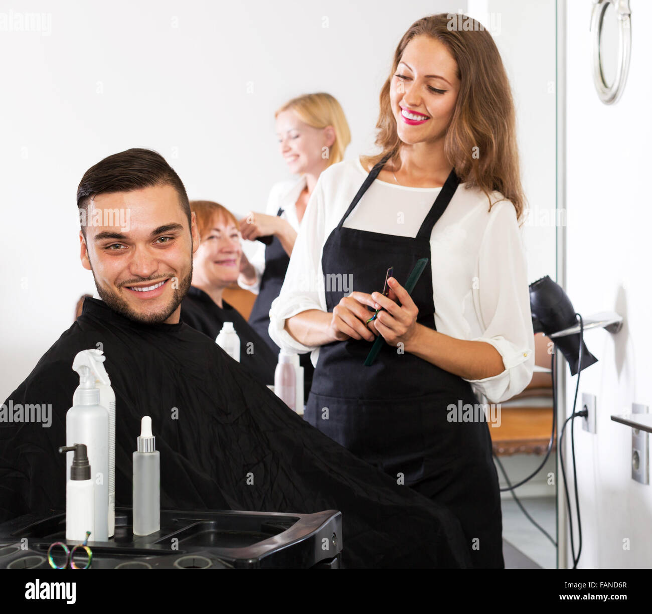 Cheerful young guy cuts hair and female barber at the hair salon Stock ...
