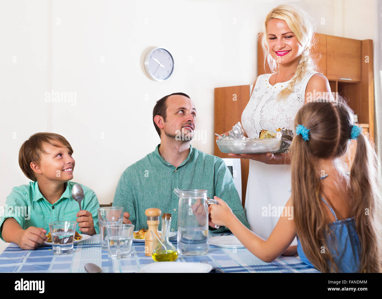 Friendly mother, father and kids sitting at the table at home and ...