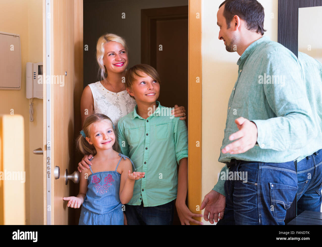 Hospitable smiling man greeting happy guests at apartment entrance ...