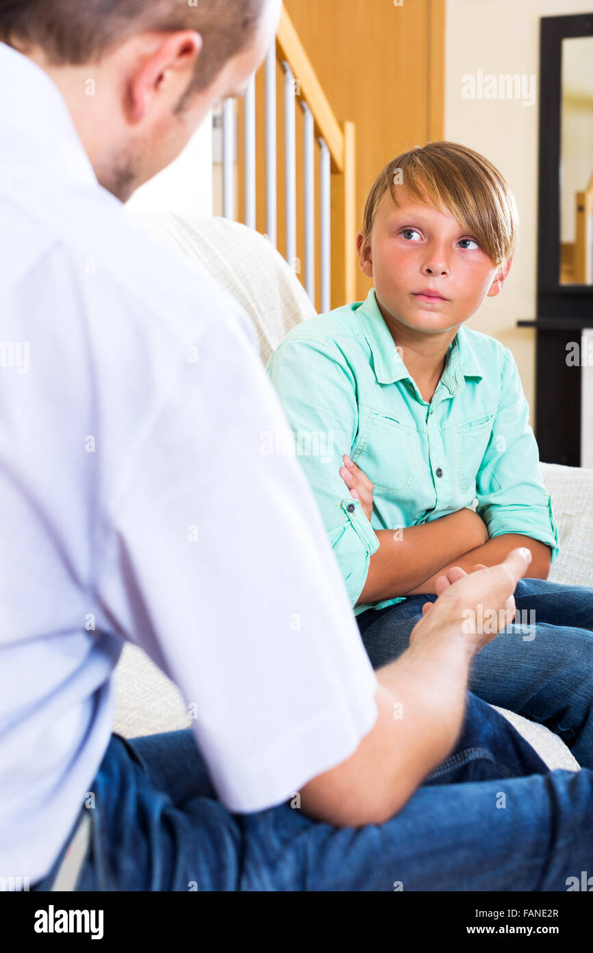 Strict father and teenage son discussing something interesting indoors ...