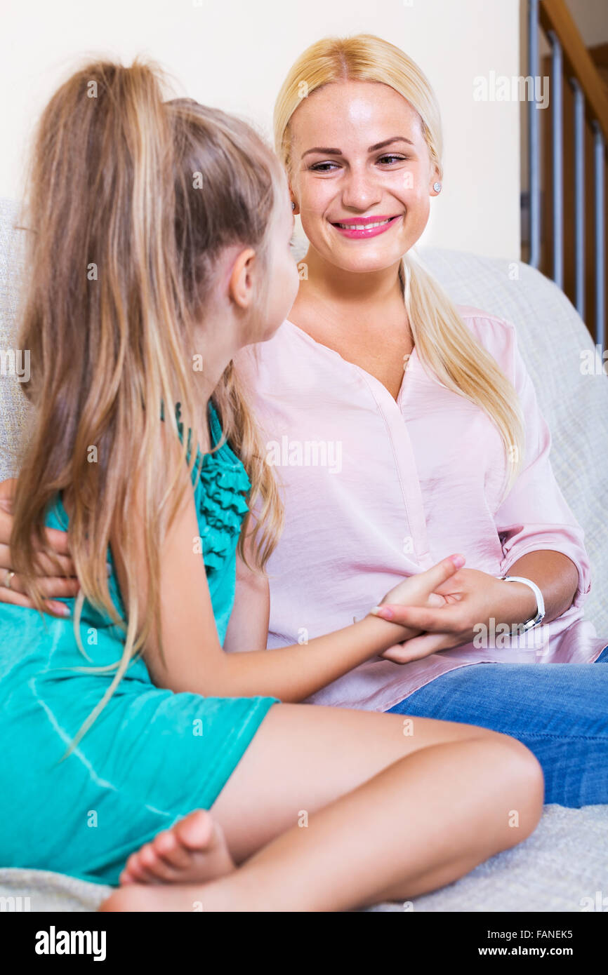Portrait of positive woman and little girl having funny conversation ...