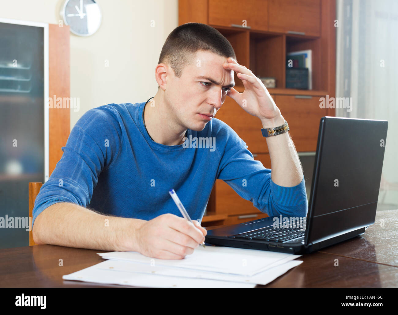 Sad frustrated guy looking at financial documents in laptop in home ...