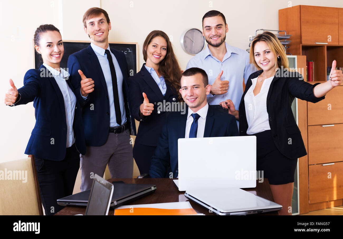 Prosperous business team smiling and posing in office. Focus on sitting ...