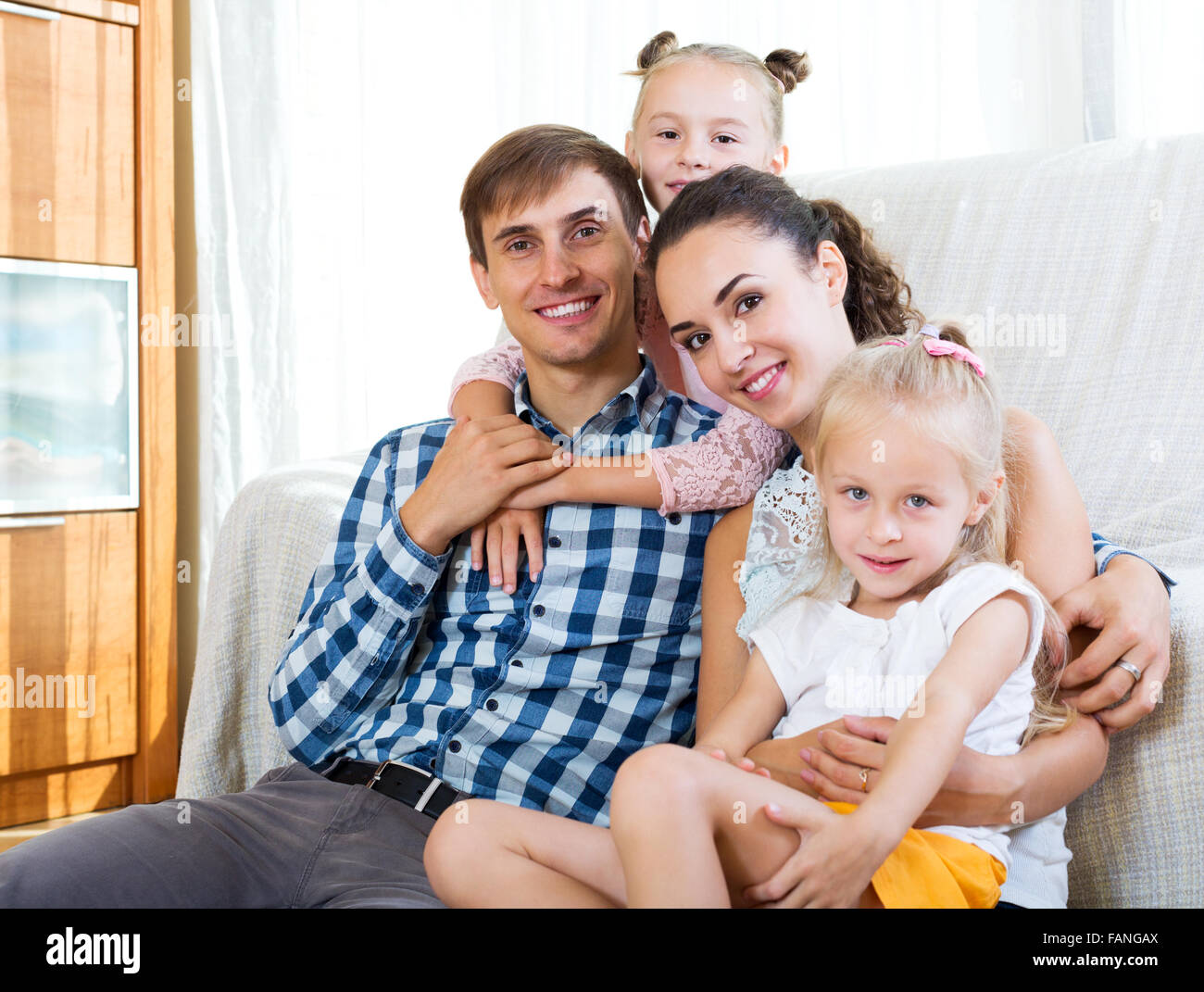 Beautiful parents with two daughters relaxing at home Stock Photo - Alamy