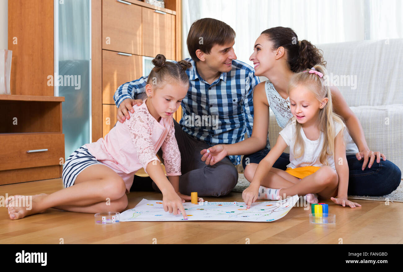 Smiling family of four playing at board game in domestic interior Stock ...