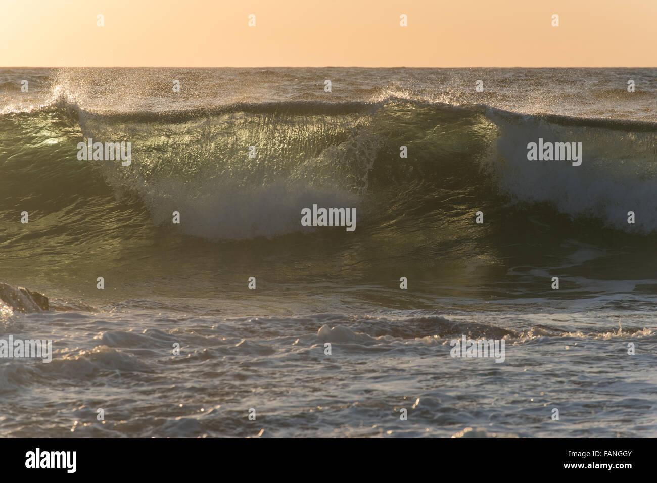 Big transparent ocean waves during sunrise with back light and green ...