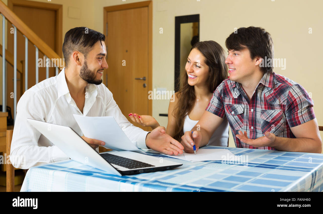 Happy young couple and smiling salesman talking cheerfully about ...