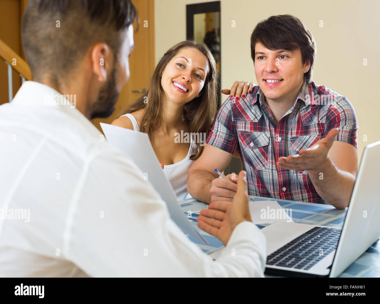 Salesman and positive young couple talking about purchase at their home ...