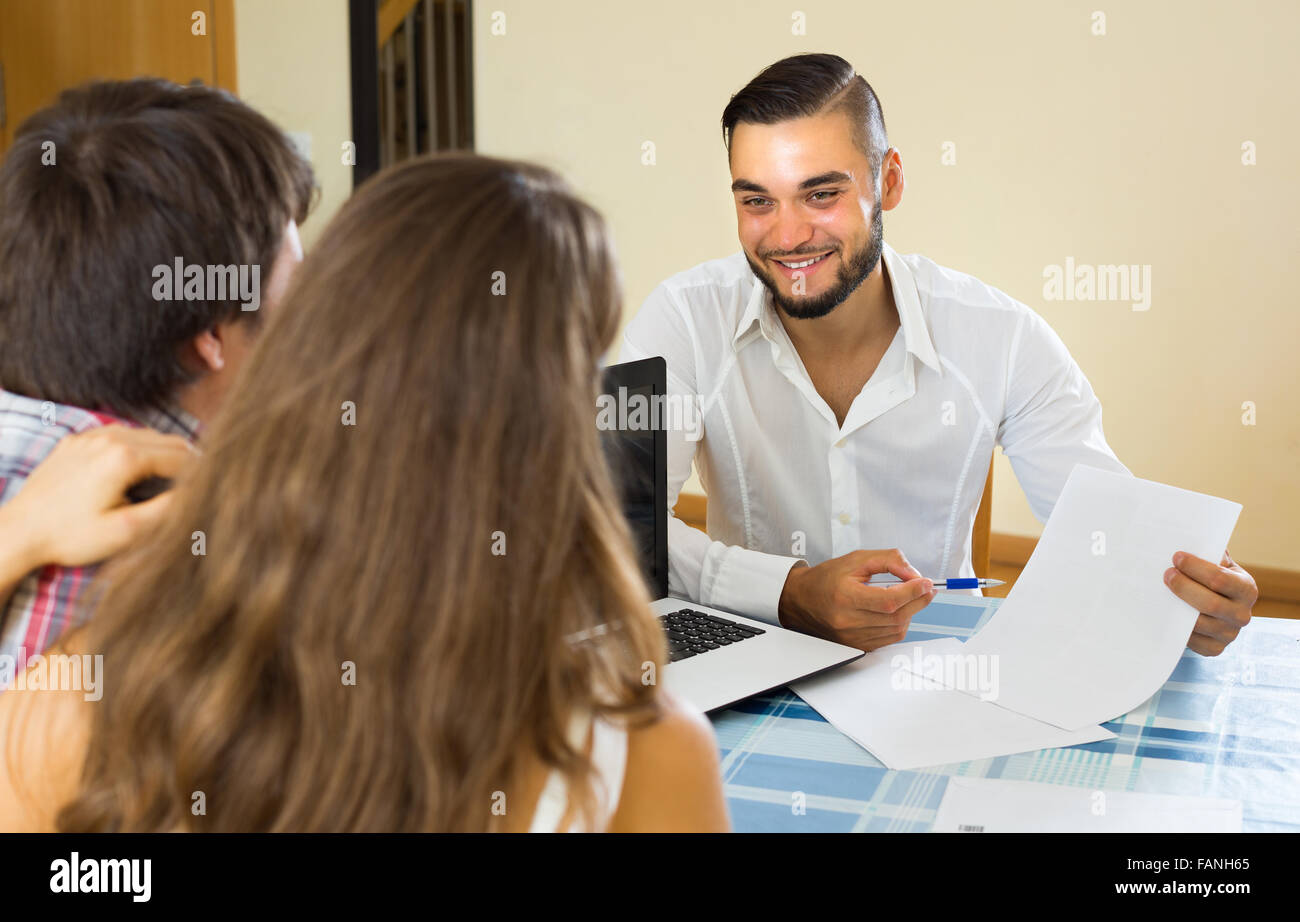 Cheerful smiling salesman and young couple talking about purchase at ...