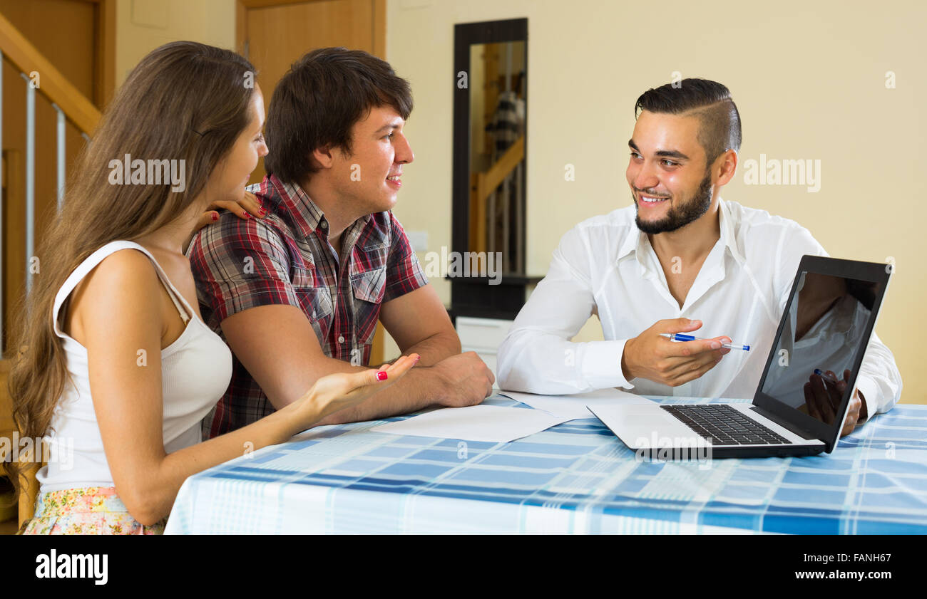 Happy smiling salesman and young couple at home talking about purchase ...