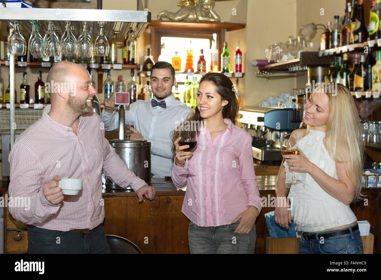 Smiling restaurant guests waiting for table and having beverages at ...