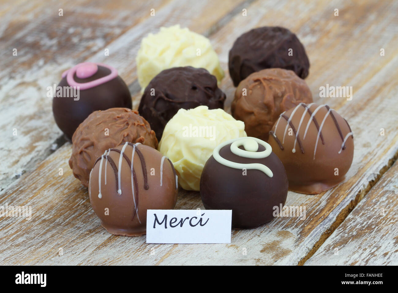 Merci (thank you in French) card with assorted chocolates on rustic ...