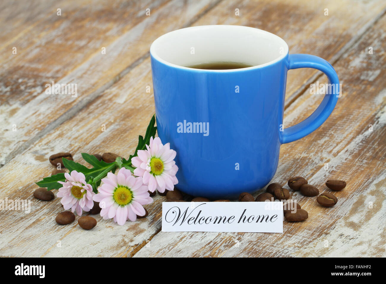 Welcome home card with mug of coffee and pink daisies on rustic wooden ...