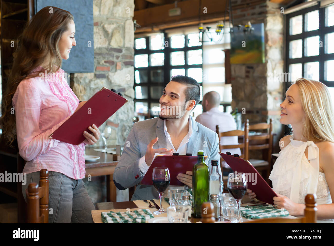 Portrait of cheerful people having dinner and respectful waiter Stock ...