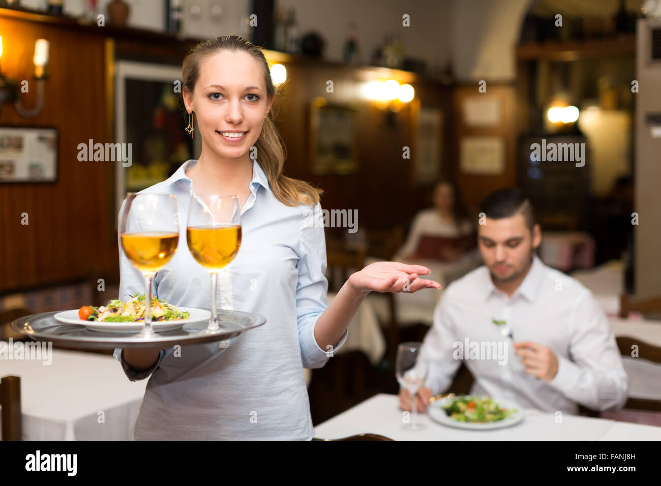 Beautiful waitress with shining smile serving clients in a restaurant ...