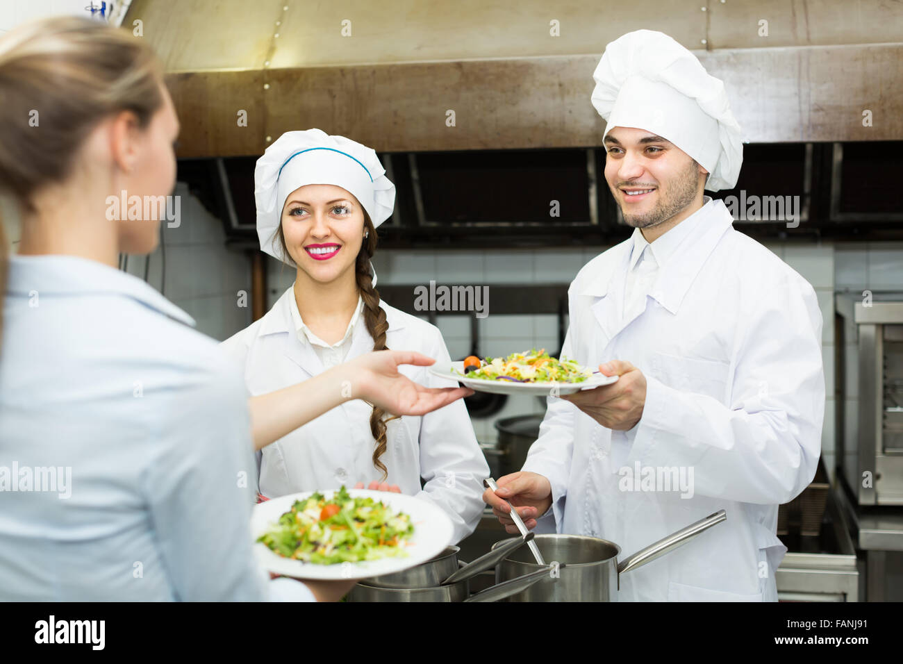 Cook gives to young waitress plates with prepared meal at restaurant's ...