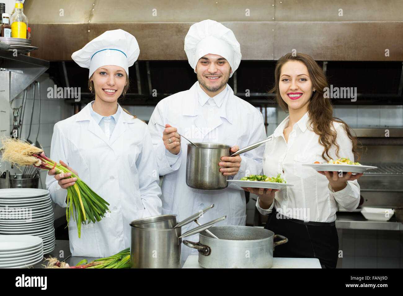 Team of positive chefs and young waiter in the restaurant kitchen Stock ...