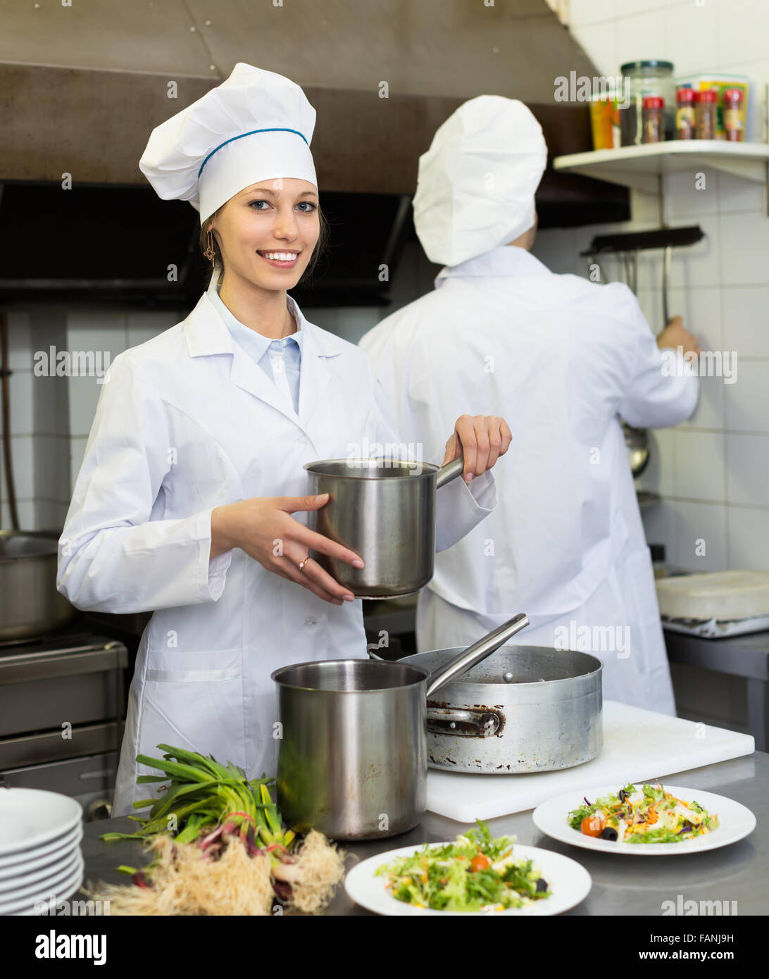 Smiling head-cooks cooking at professional kitchen in the restaurant ...