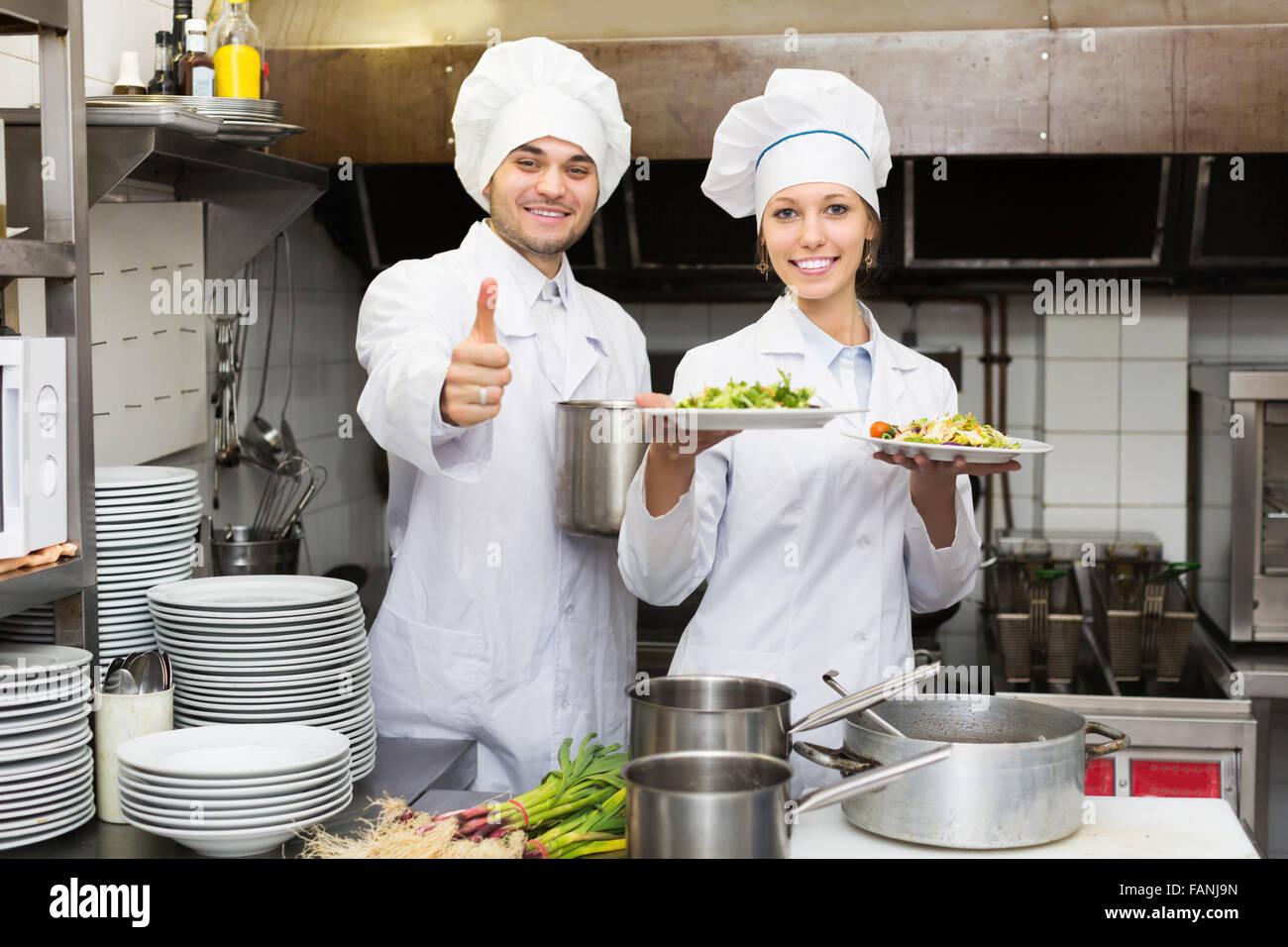Two positive professional cookes working at restaurant kitchen Stock ...