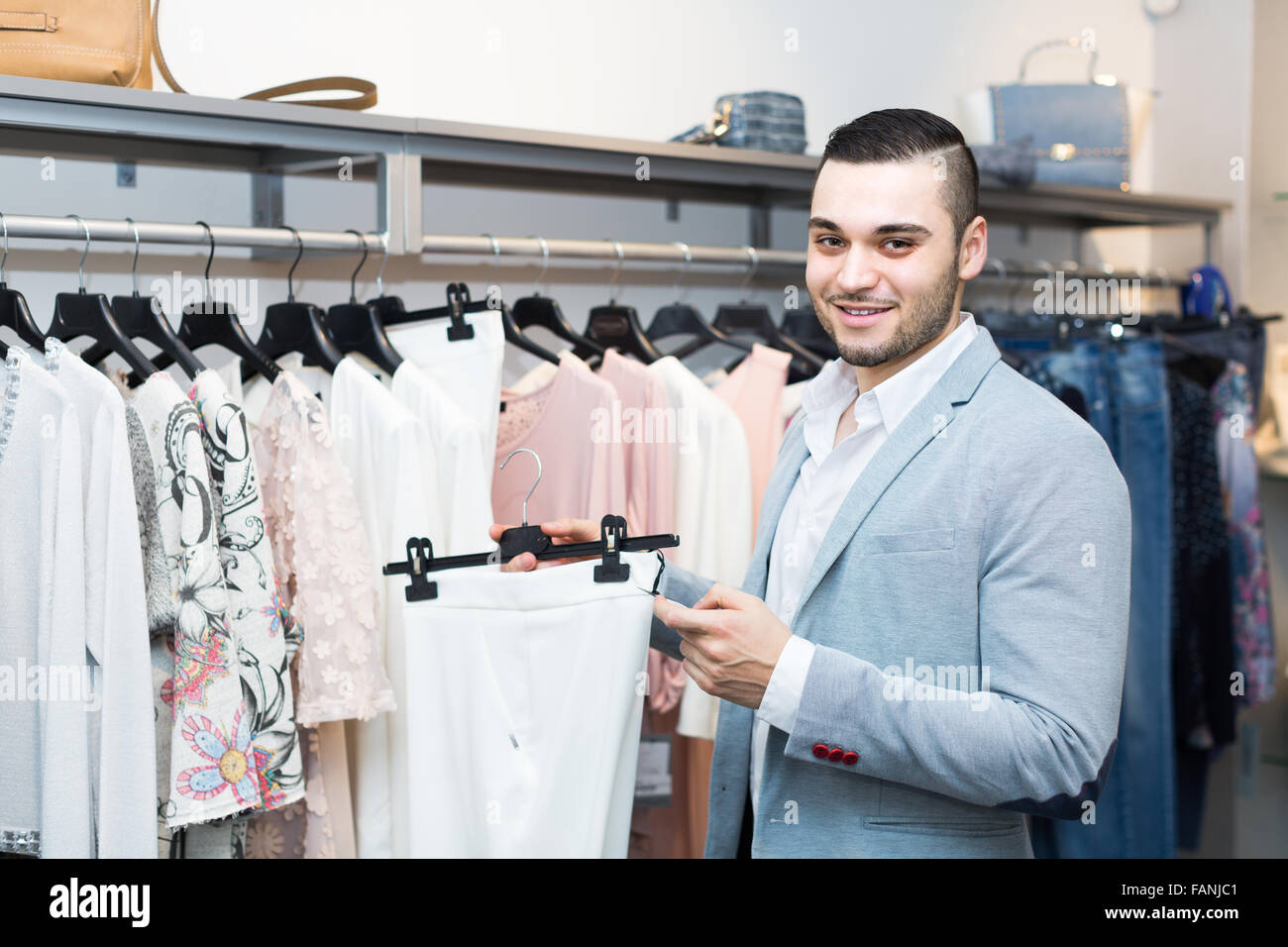 Positive young man buying clothes for his girlfriend at boutique Stock ...