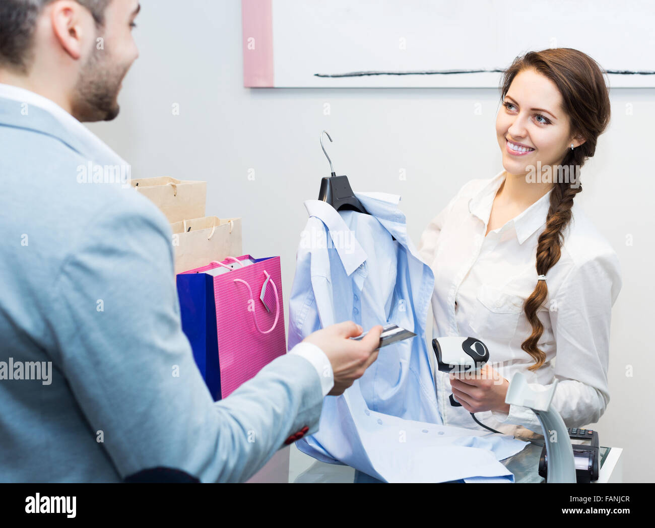 Happy store clerk serving purchaser at cash register desk Stock Photo ...
