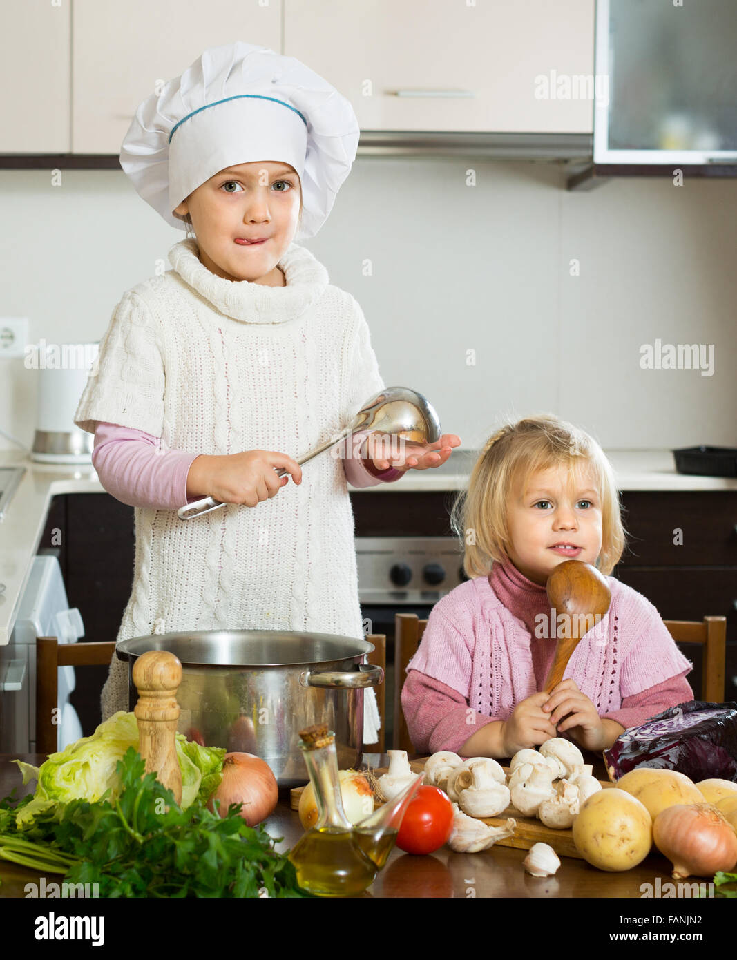 Two happy little girls learning how to cook at domestic kitchen Stock ...