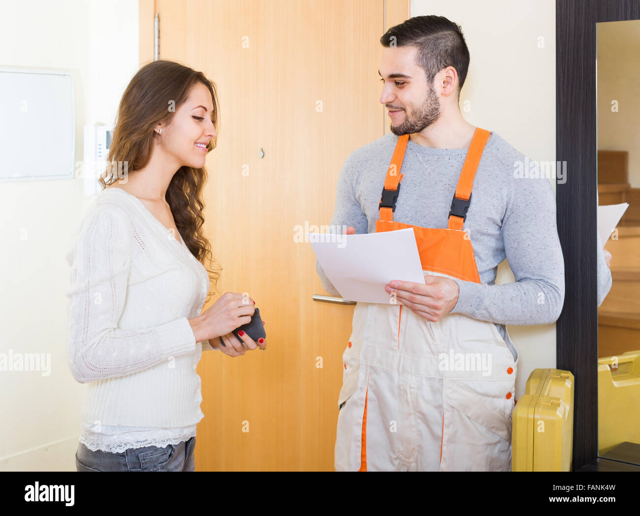 Smiling housewife meeting service worker at the door at home Stock ...