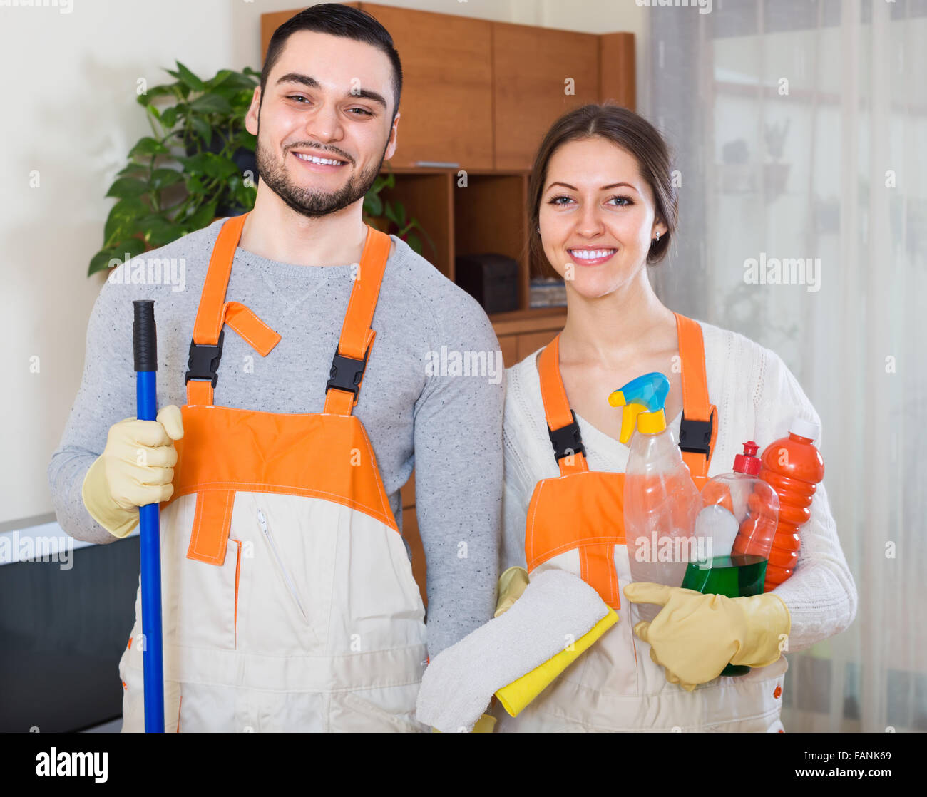 Portrait of smiling professional cleaners with equipment at client ...