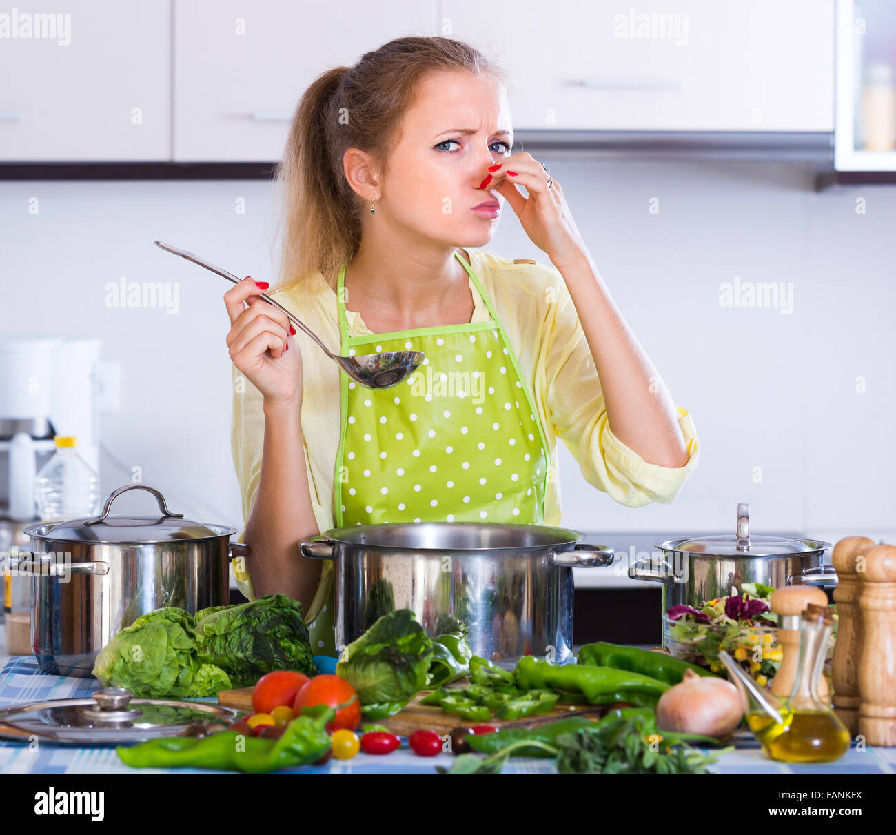 Worried young housewife smelling stale soup indoors Stock Photo - Alamy