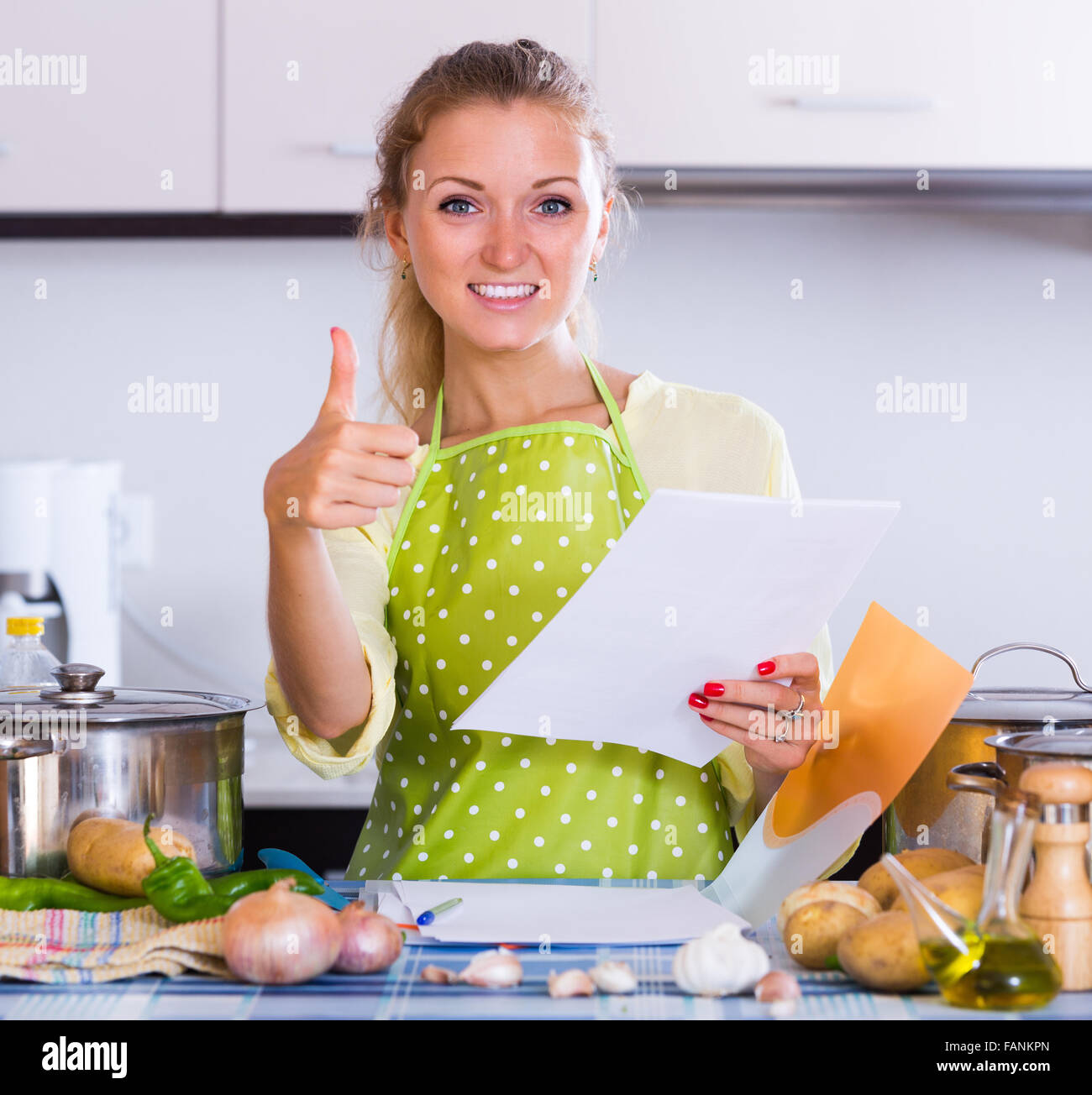 Happy smiling young housewife filling banking forms at home kitchen ...