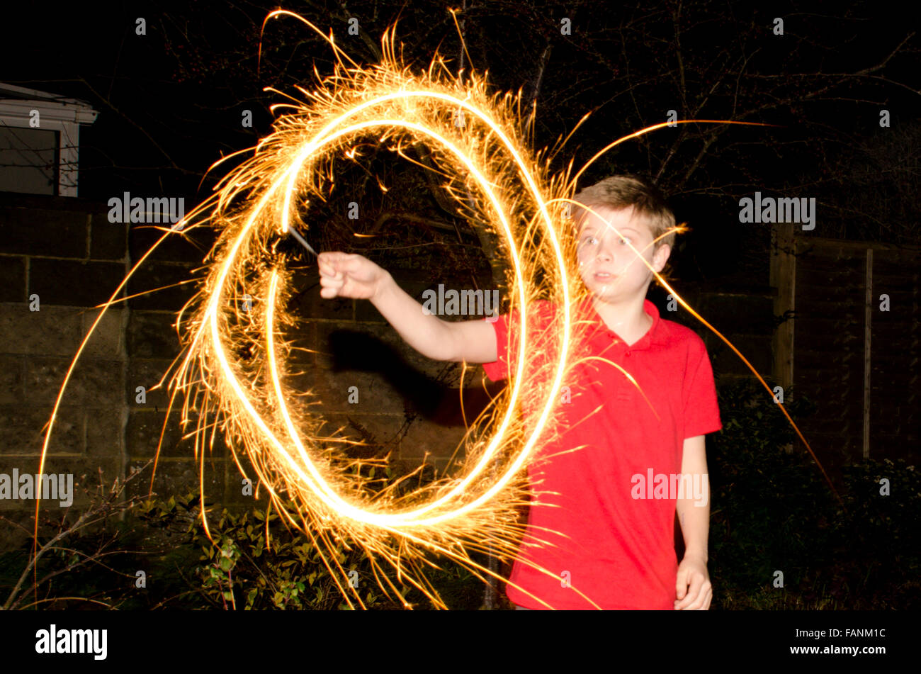 Nine-year-old boy holding firework sparkler and twirling it round in ...