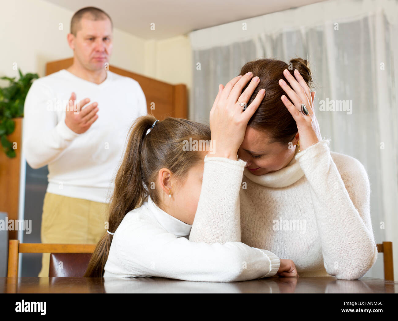 Young mother gives solace to crying daughter at home and angry father ...