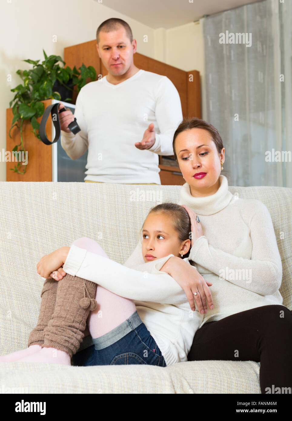 Sad mother comforting daughter at home and angry father Stock Photo - Alamy