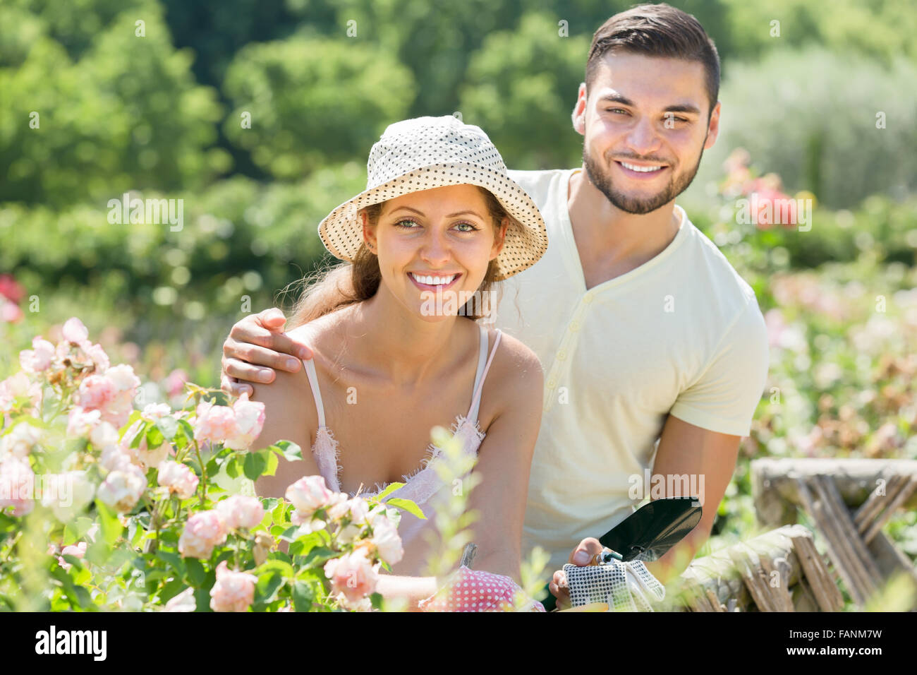 Cheerful couple gardeners planting plants in the garden Stock Photo - Alamy