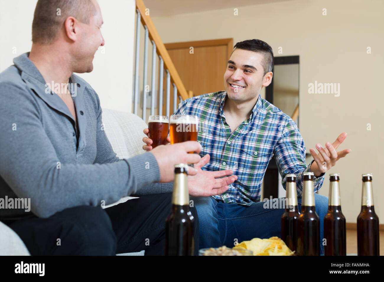 Two adult men with beer at the table indoor Stock Photo - Alamy