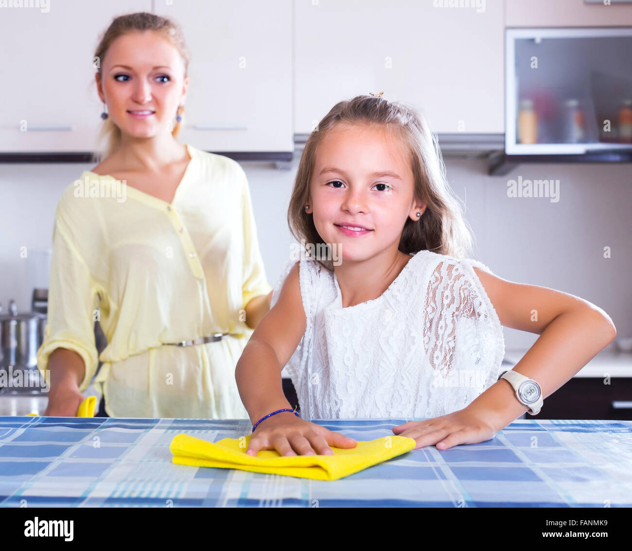 Cute girl helping adult mom dusting in the kitchen Stock Photo - Alamy
