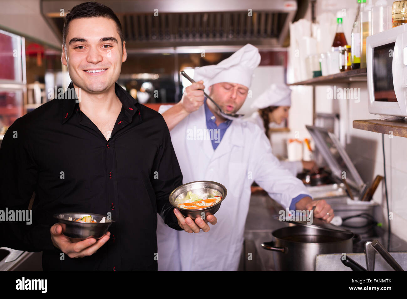 Chefs and smiling waiter working at eating house Stock Photo - Alamy