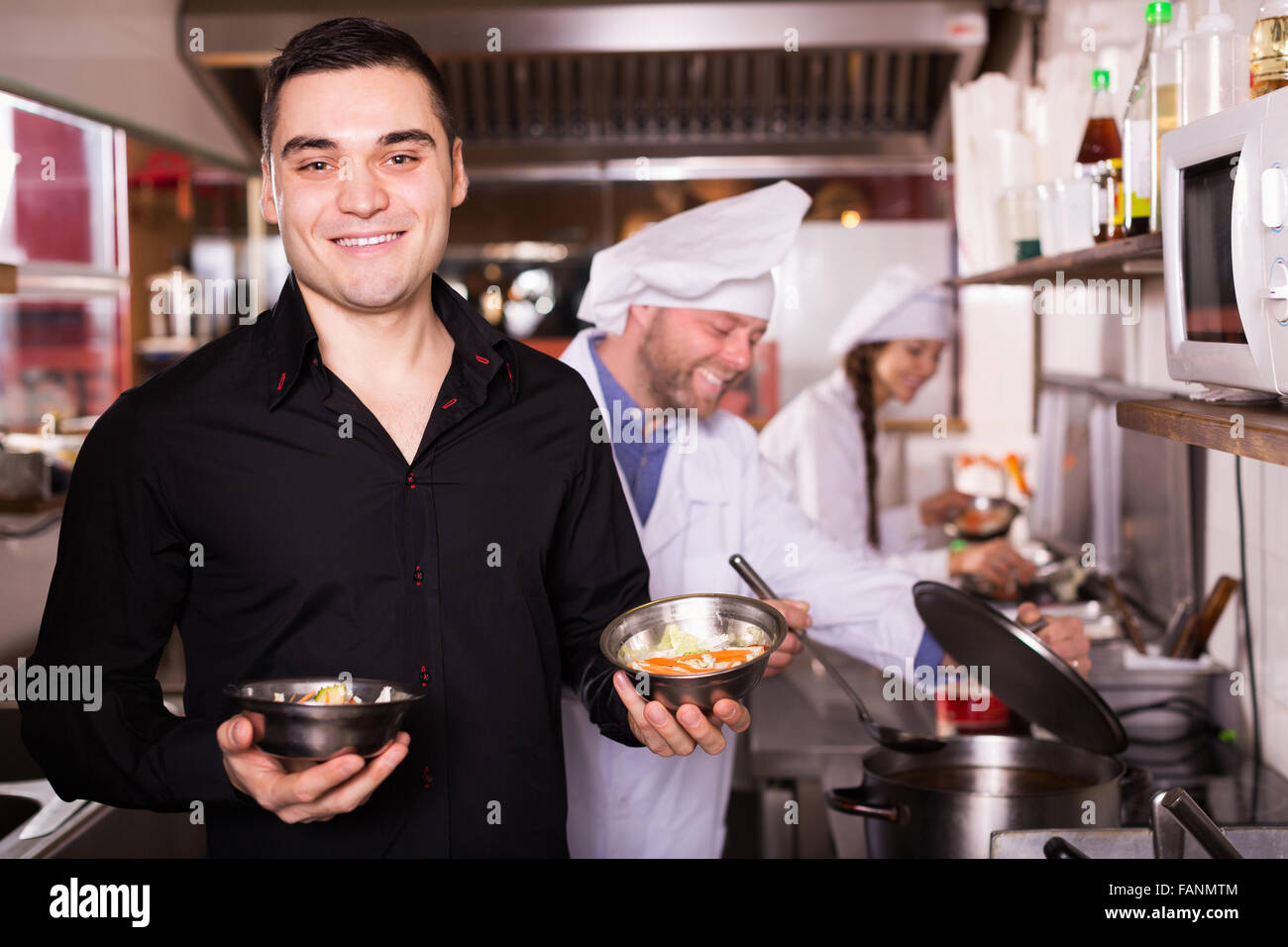 Chefs and happy waiter working at eating house Stock Photo - Alamy