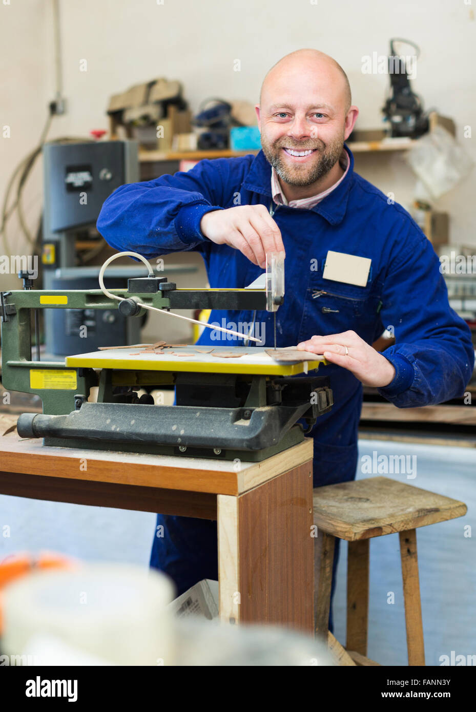 Positive professional woodworker on lathe at musical instrument ...