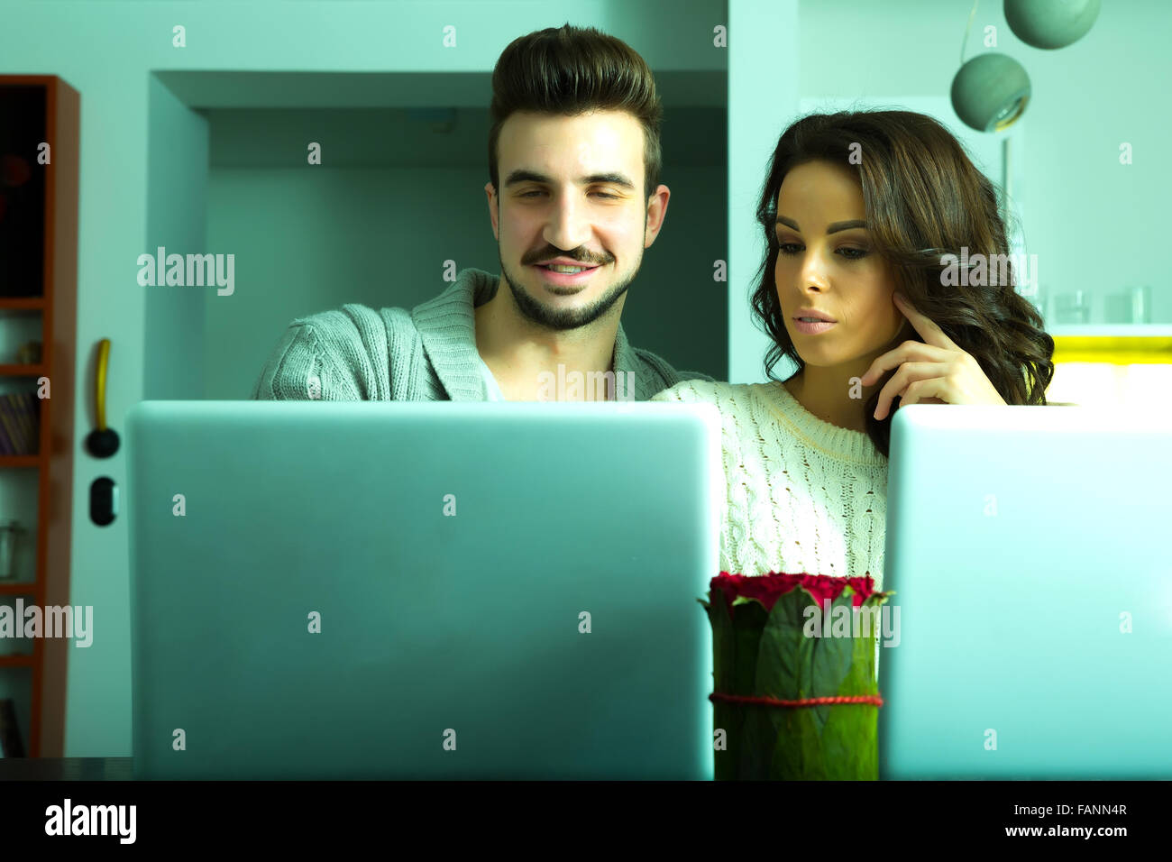 A young couple using in the evening their laptop computers at home and ...