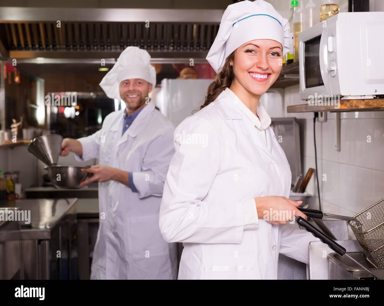 Portrait of smiling chef and his young beautiful female helper at ...